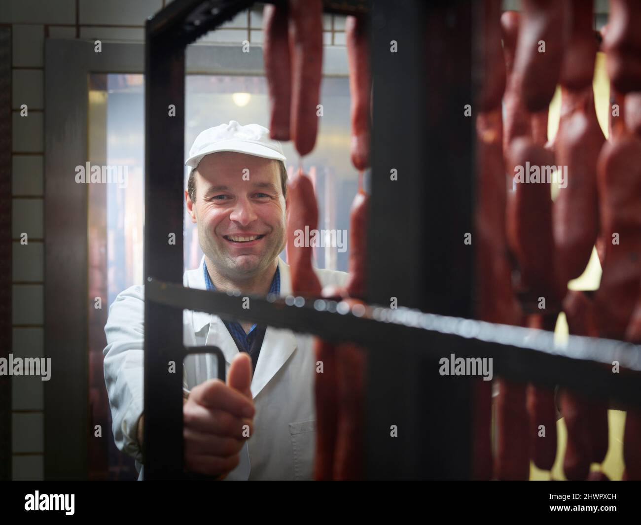 Happy butcher working in smokehouse at factory Stock Photo - Alamy