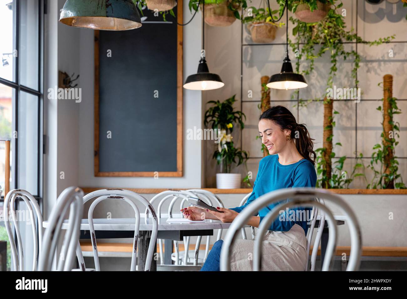 Smiling barista calculating at table in illuminated cafe Stock Photo ...