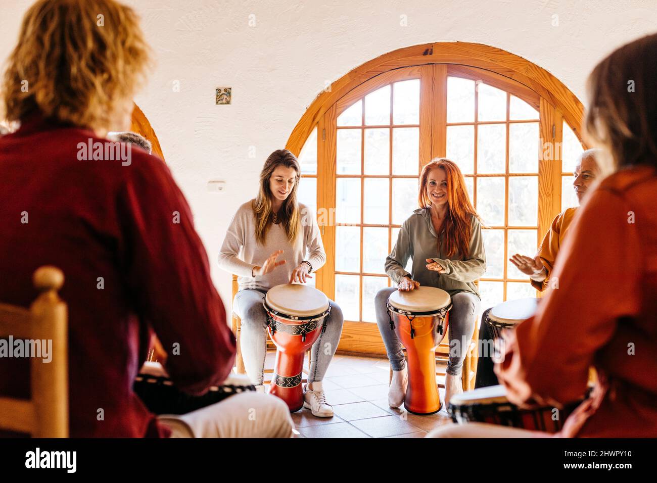 Smiling friends playing bongo at music therapy Stock Photo - Alamy