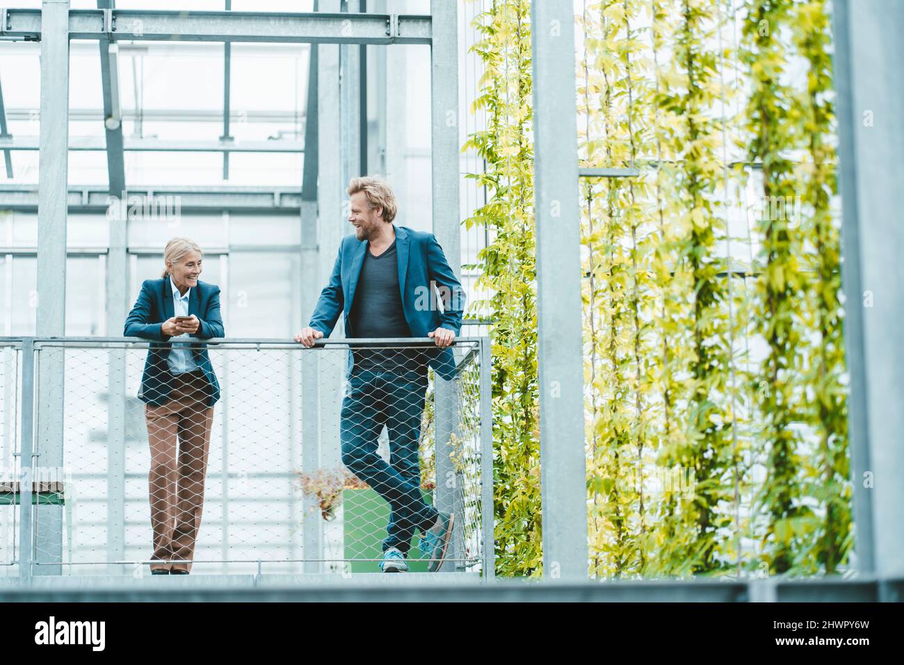 Agronomist discussing with coworker by railing in plant nursery Stock ...
