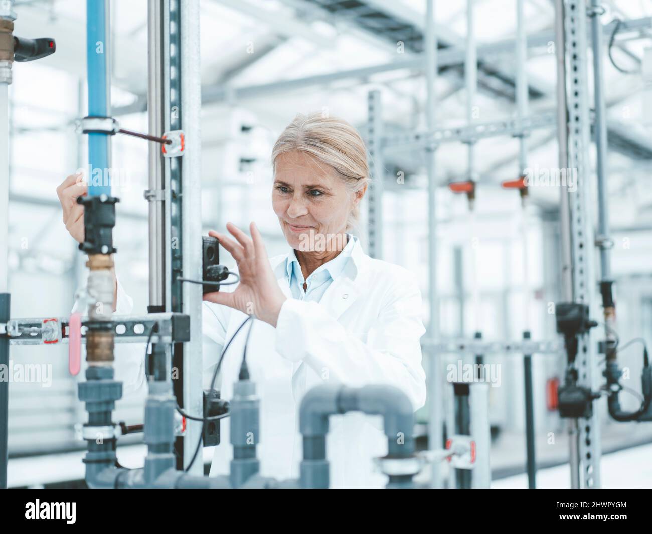 Scientist examining pipes and machinery in industry Stock Photo - Alamy