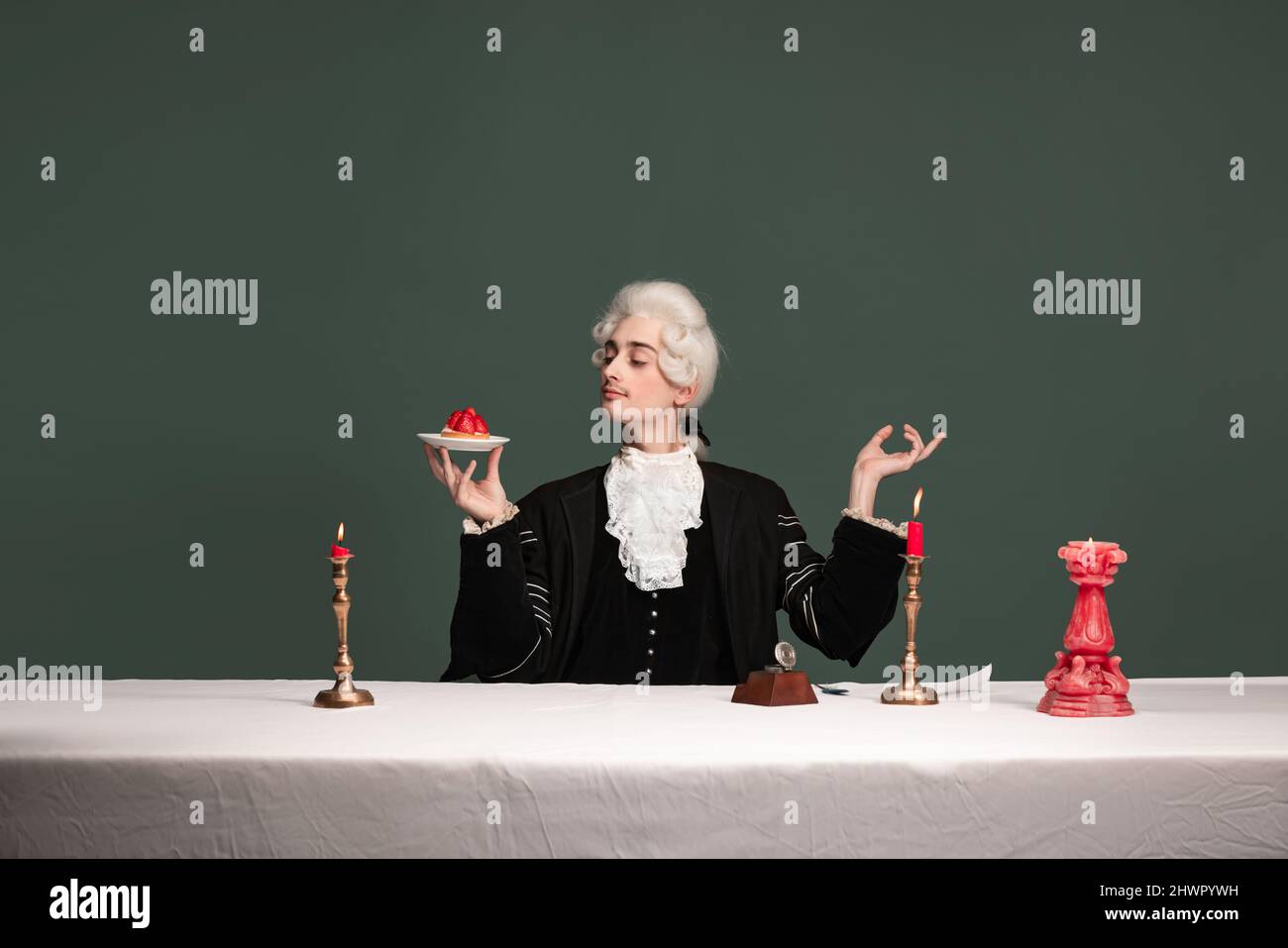 Portrait of young elegant man in peruke and vintage jacket sitting at ...