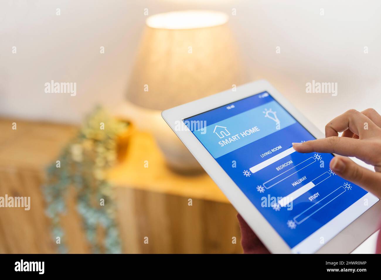 Woman adjusting lighting equipment through tablet PC in smart home ...