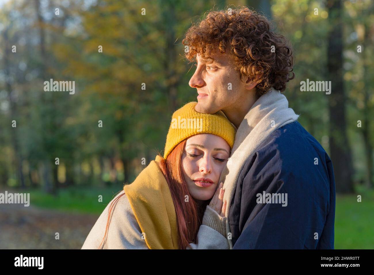 Redhead woman leaning on boyfriend's chest at park Stock Photo - Alamy
