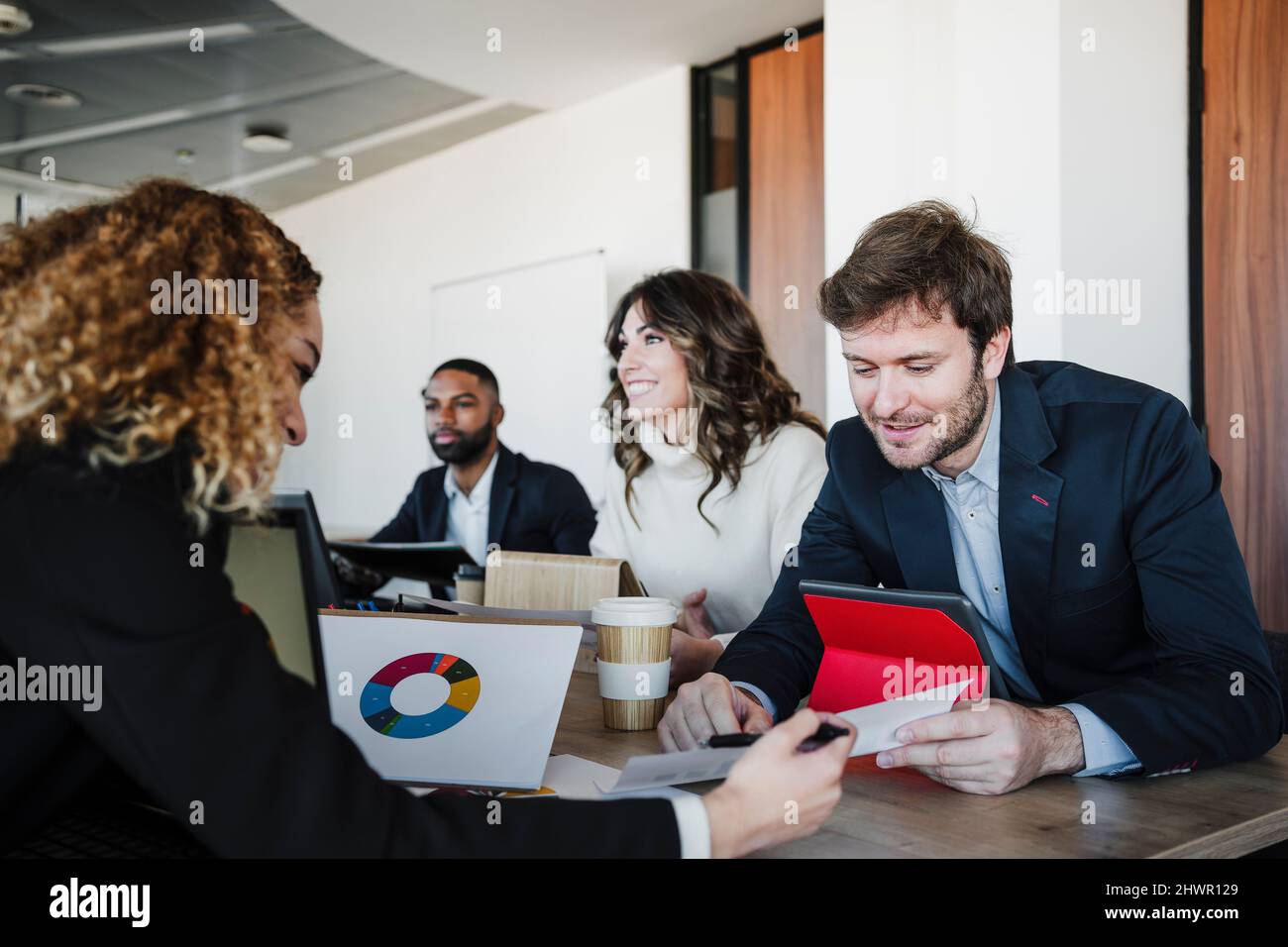 Businessman explaining document to young colleague in office Stock ...
