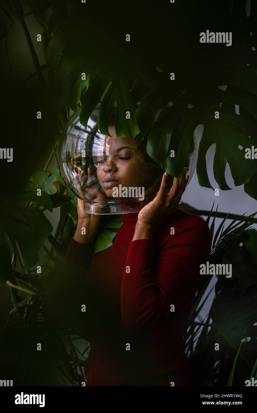 Woman with eyes closed wearing pot on face by plants Stock Photo - Alamy
