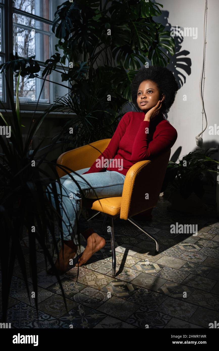 Contemplative woman sitting on chair at home Stock Photo - Alamy