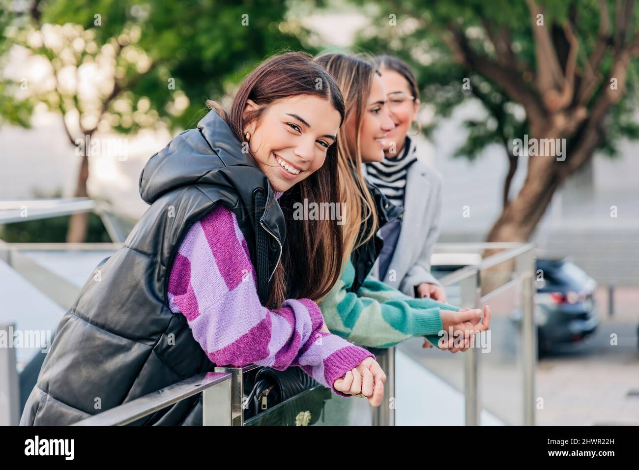 Smiling young woman standing by friends in city Stock Photo - Alamy