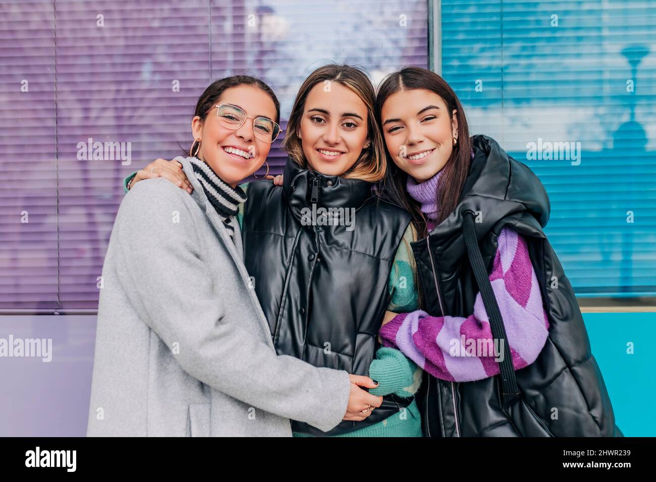 Smiling friends standing in front of wall Stock Photo - Alamy