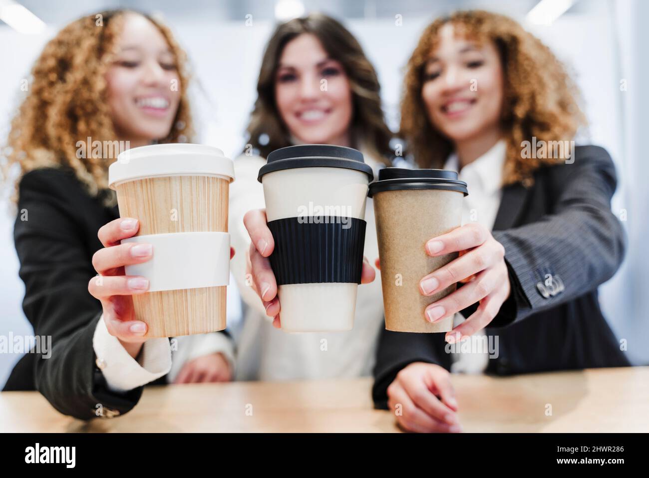 Business colleagues holding disposable coffee cups at coworking office ...