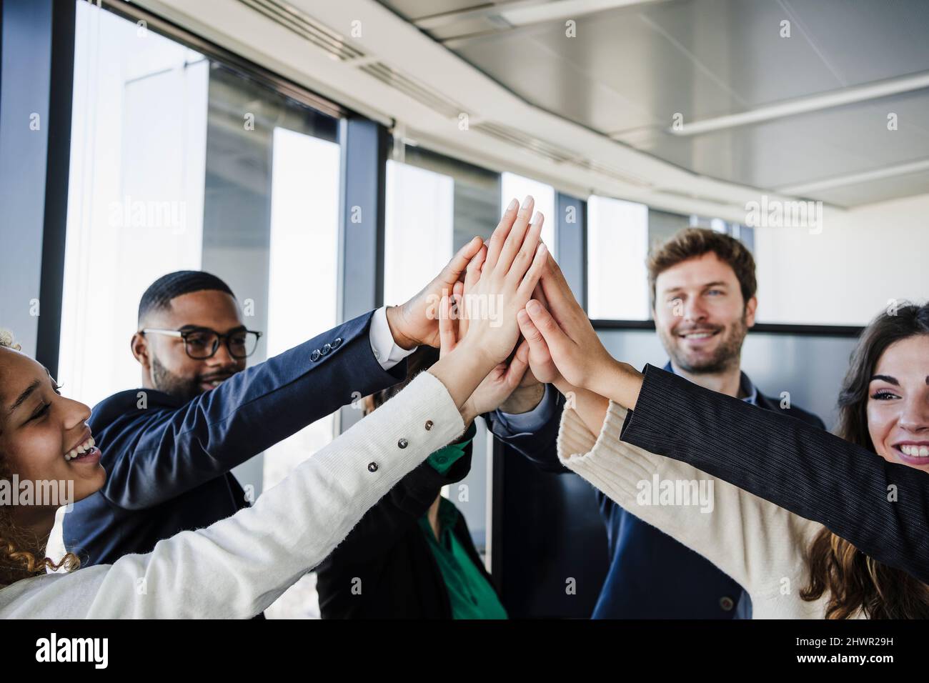 Happy business colleagues with stacked hands in office Stock Photo - Alamy