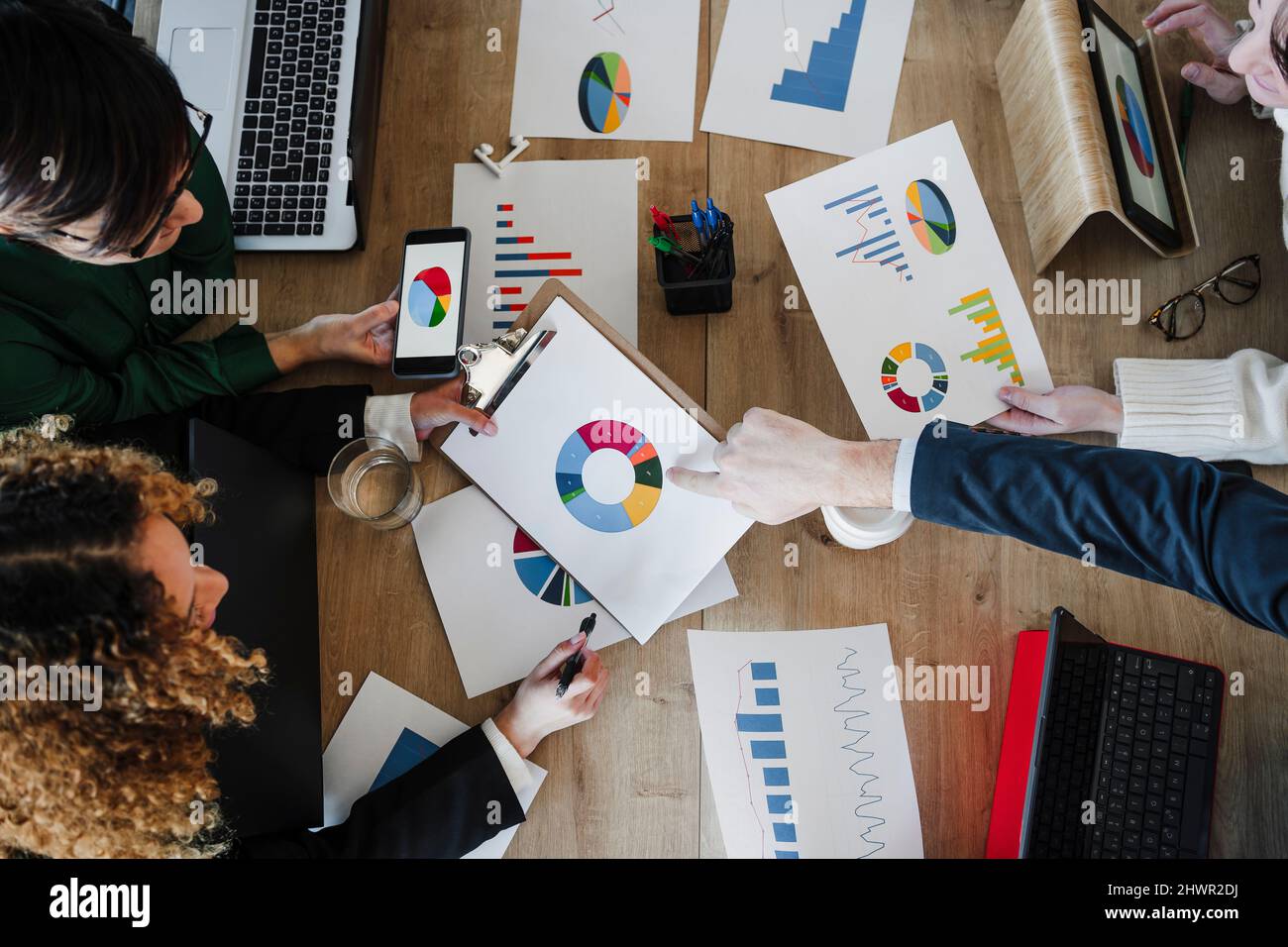 Business colleagues discussing over pie chart at desk in coworking ...