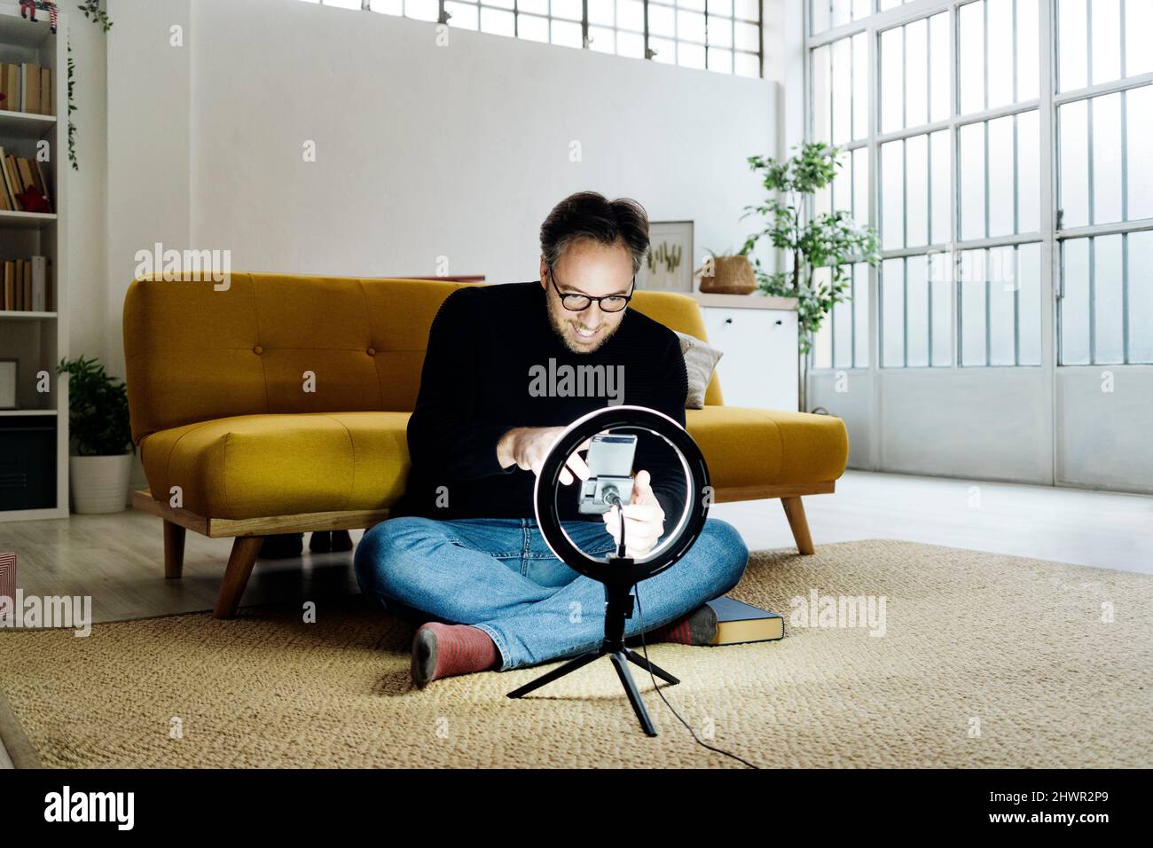 Smiling mature man with smart phone vlogging at home Stock Photo - Alamy