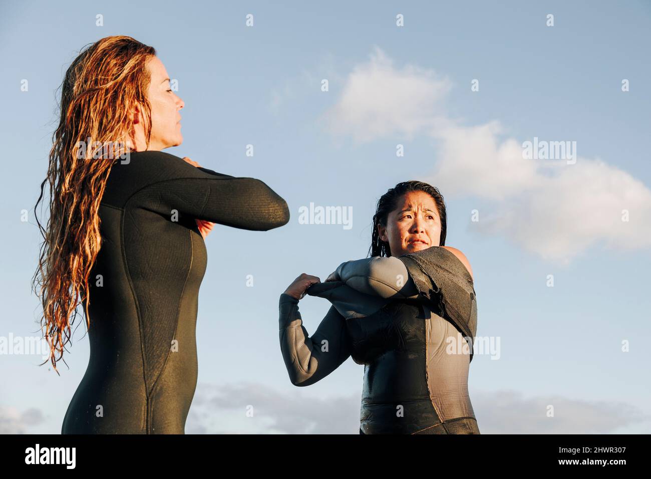 Female surfers removing wetsuit after surfing Stock Photo - Alamy