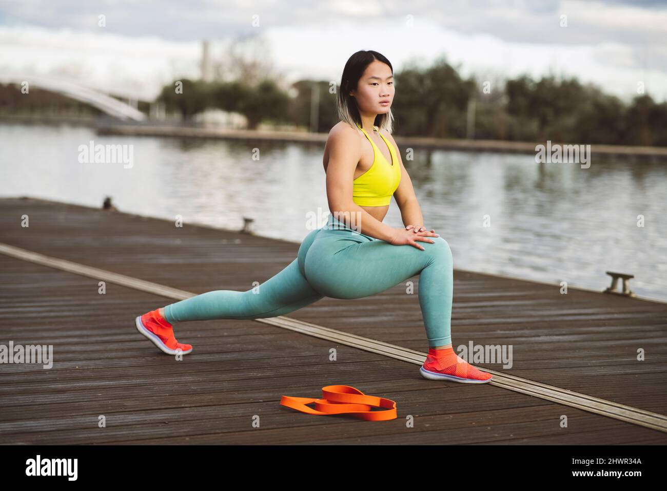 Young athlete doing warm-up exercise on jetty at lakeside Stock Photo ...