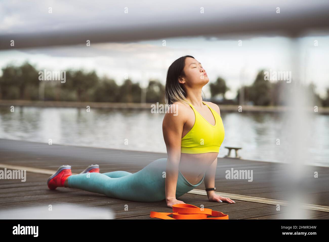 Active woman doing cobra stretch with eyes closed on jetty Stock Photo ...