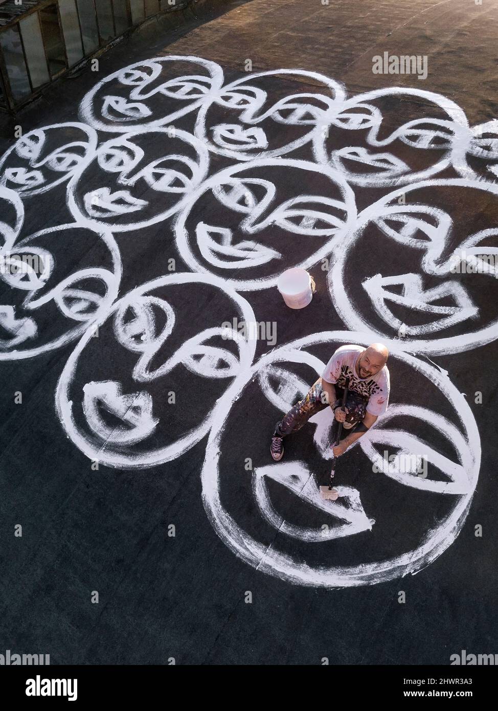Artist painting smiley faces on roof Stock Photo - Alamy
