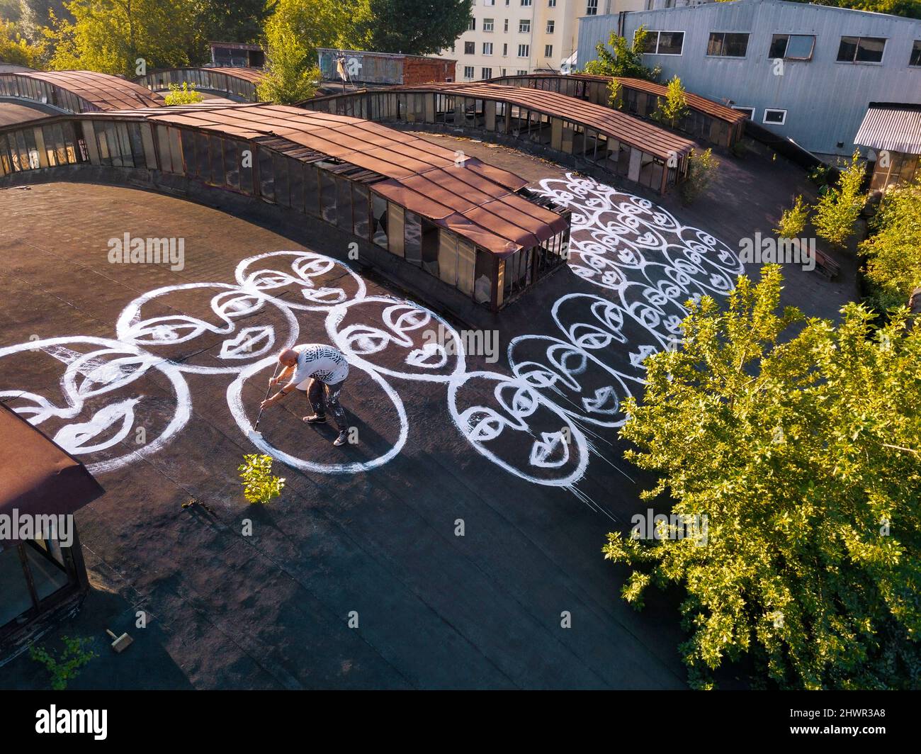 Painter painting smiley graffiti on rooftop Stock Photo - Alamy