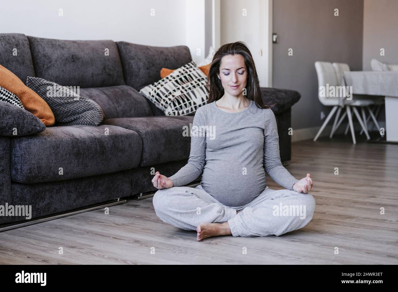 Pregnant woman practicing lotus position at home Stock Photo - Alamy