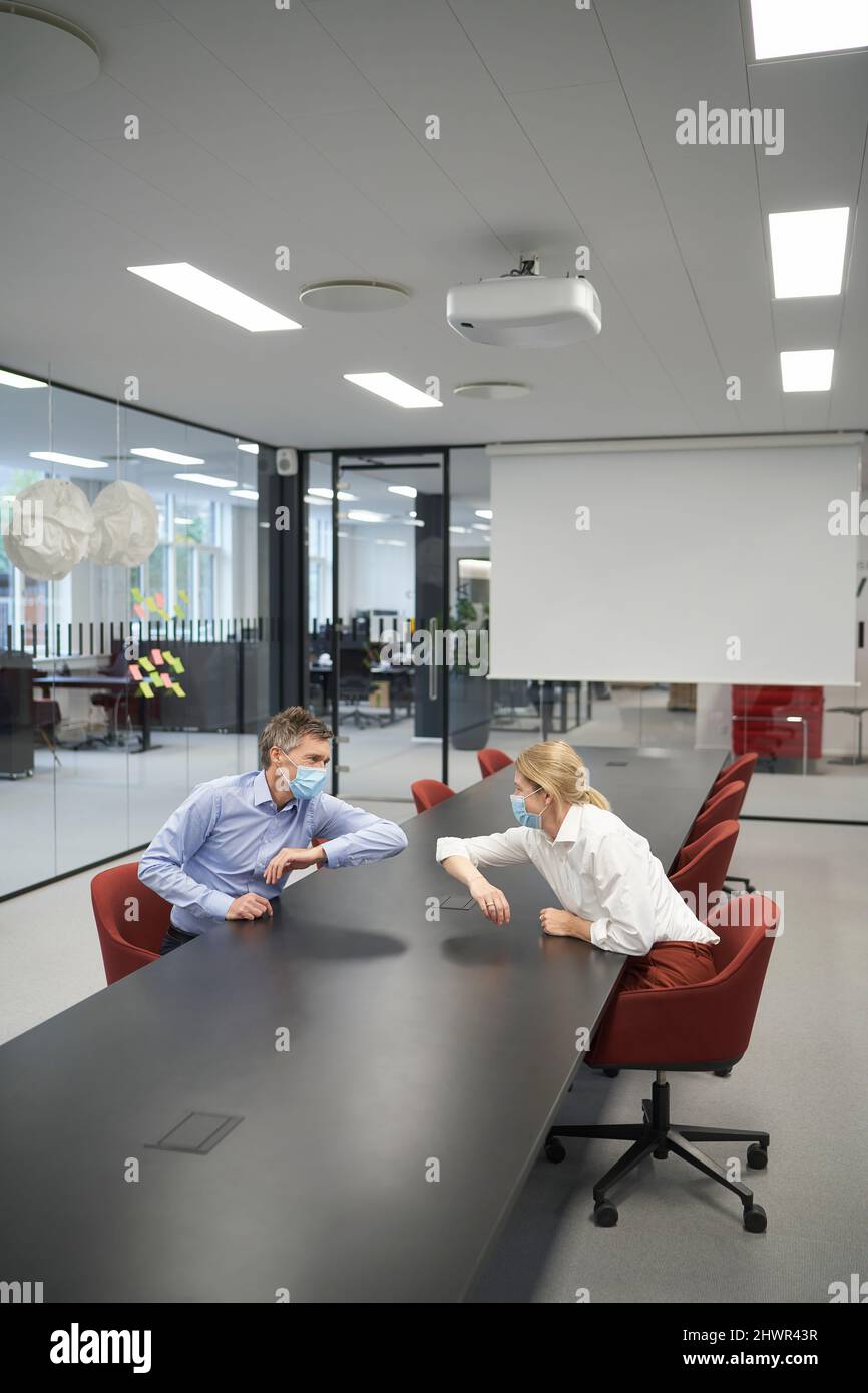 Businessman doing elbow bump with colleague in office Stock Photo - Alamy