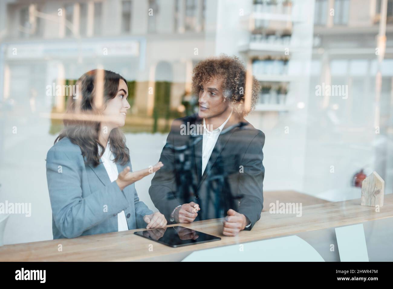 Young businesswoman discussing with businessman at desk in coworking ...