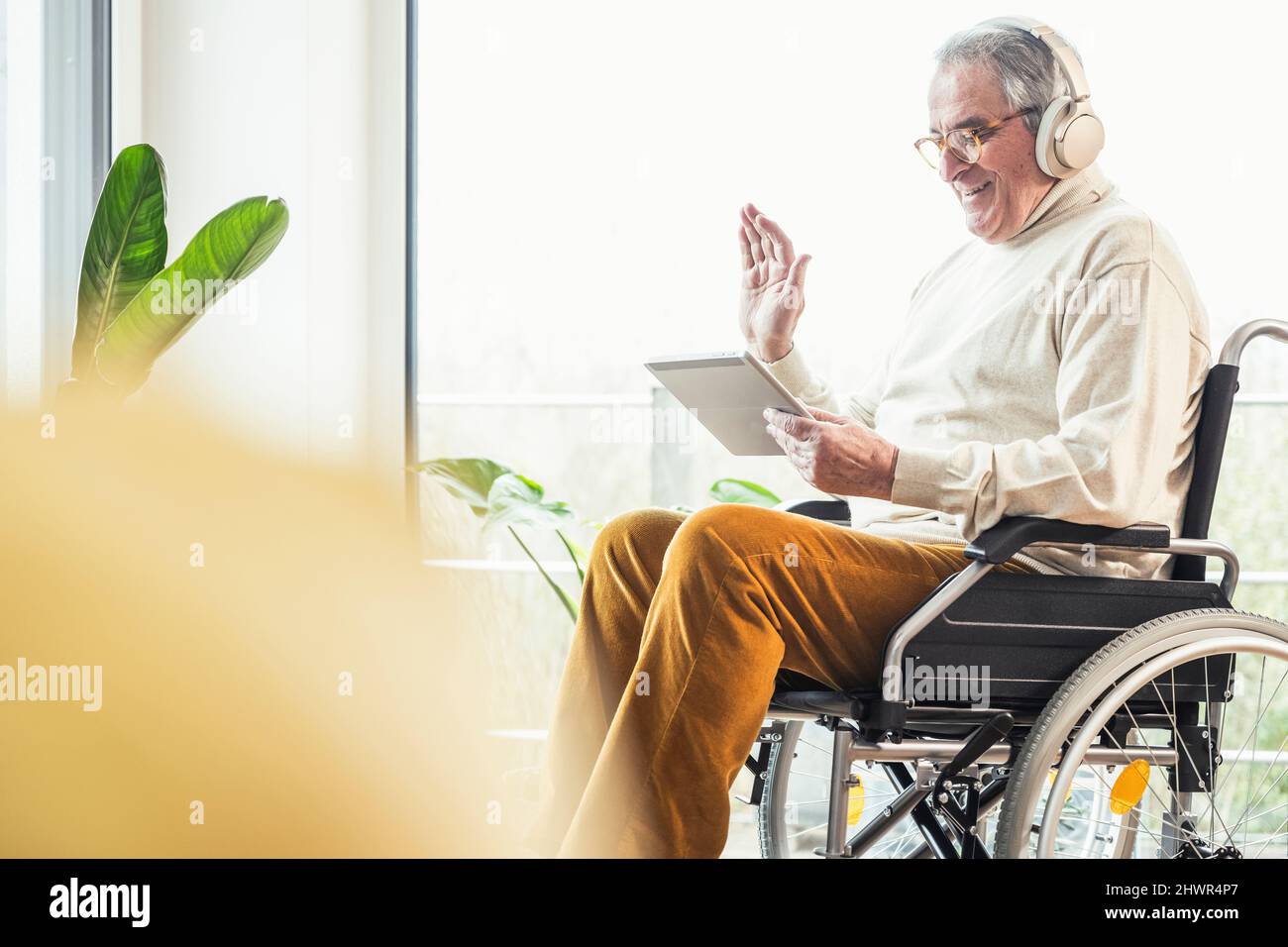 Smiling disabled man waving hand on video call through tablet PC at ...