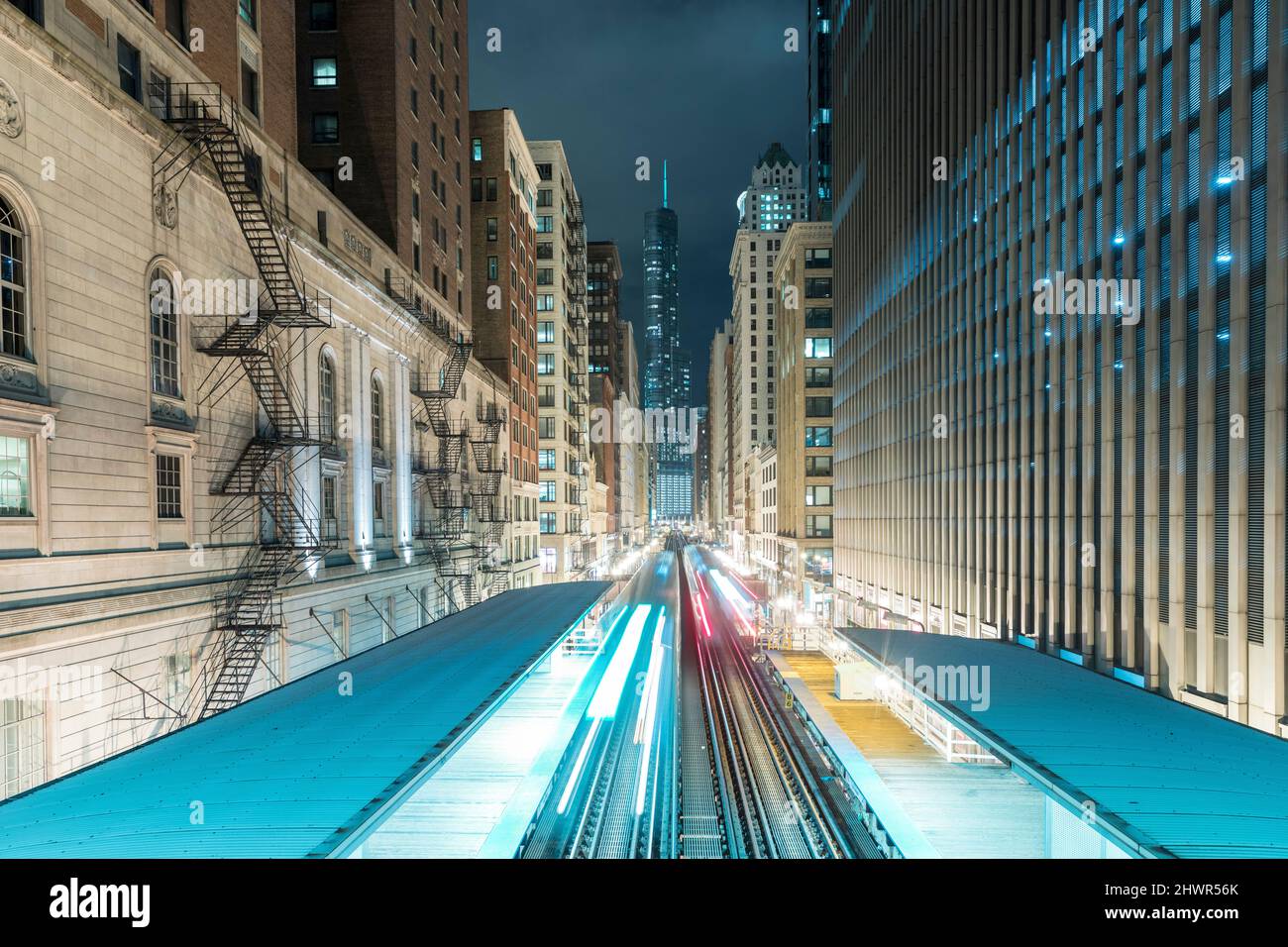 Light trails on railroad tracks amidst buildings in city at night ...