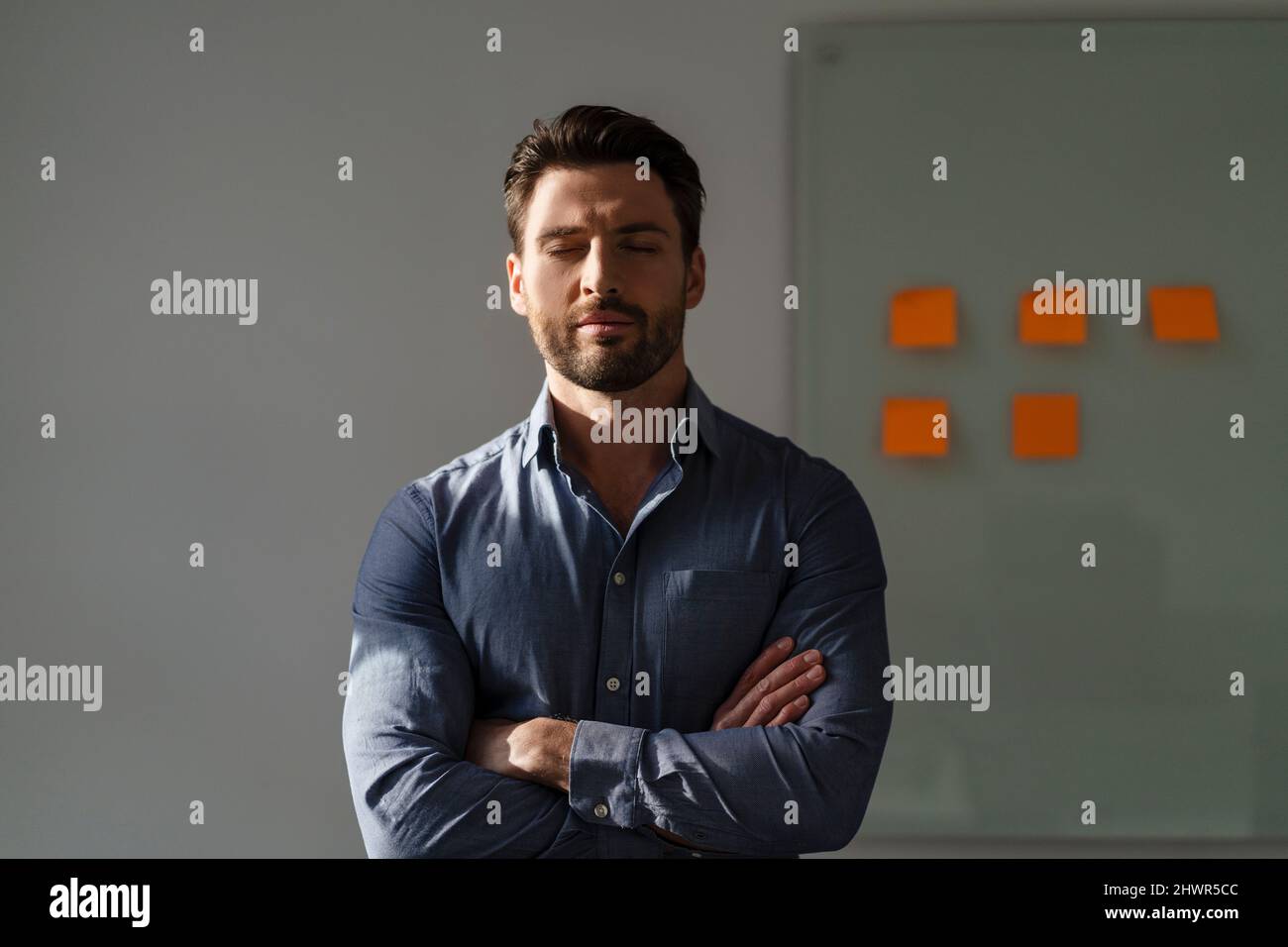 Businessman with arms crossed and eyes closed at work place Stock Photo ...