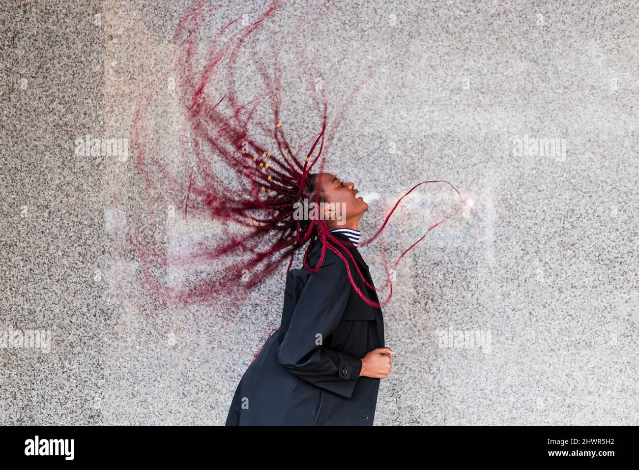 Young woman tossing hair by wall Stock Photo - Alamy