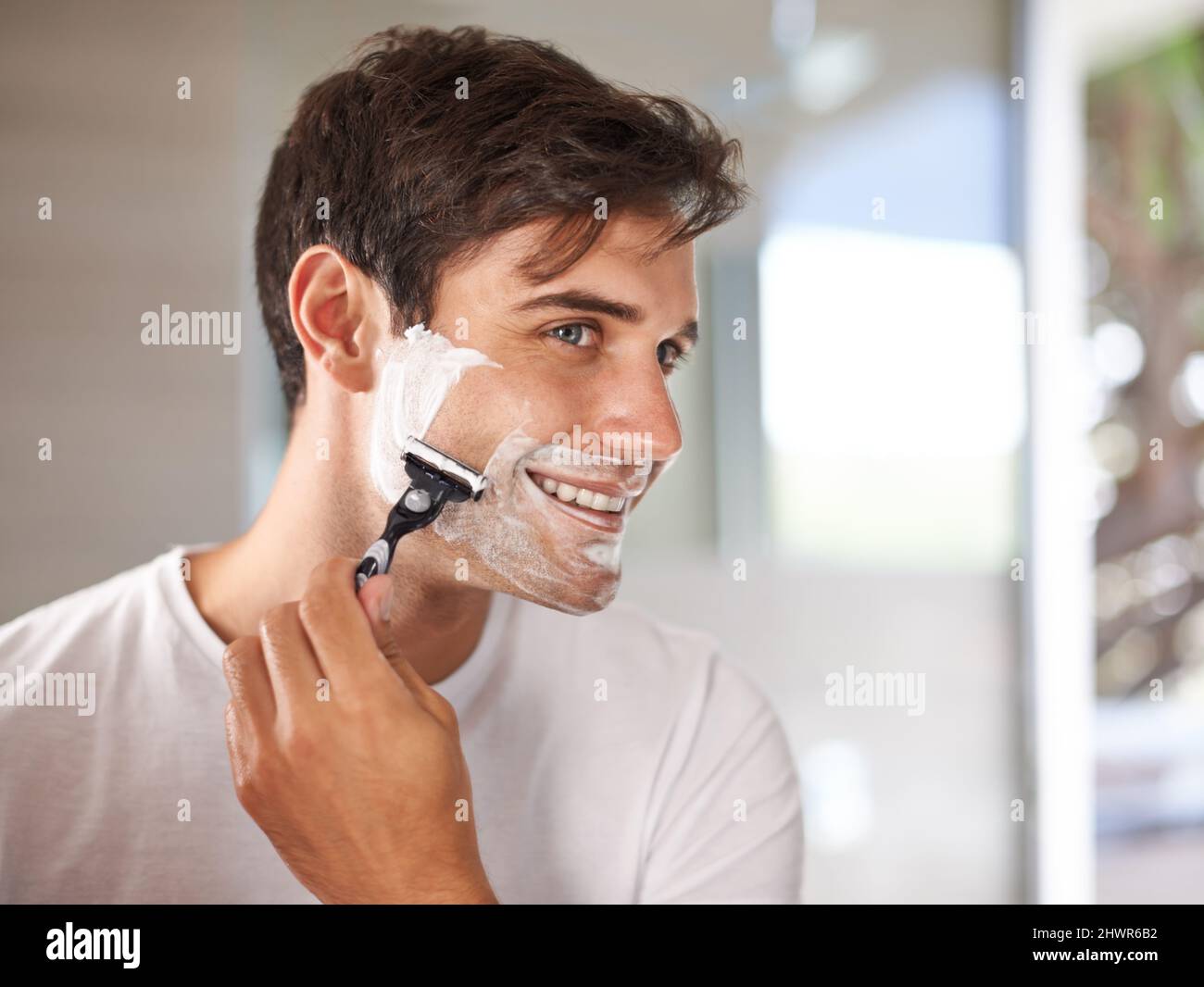 Enjoying his morning routine. Cropped shot of a young man shaving his ...