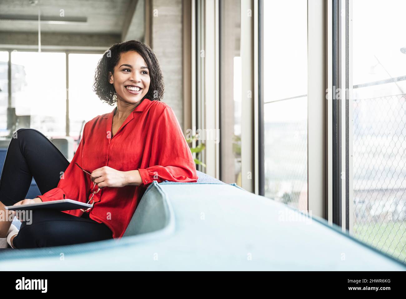 Businesswoman looking through window in office Stock Photo - Alamy