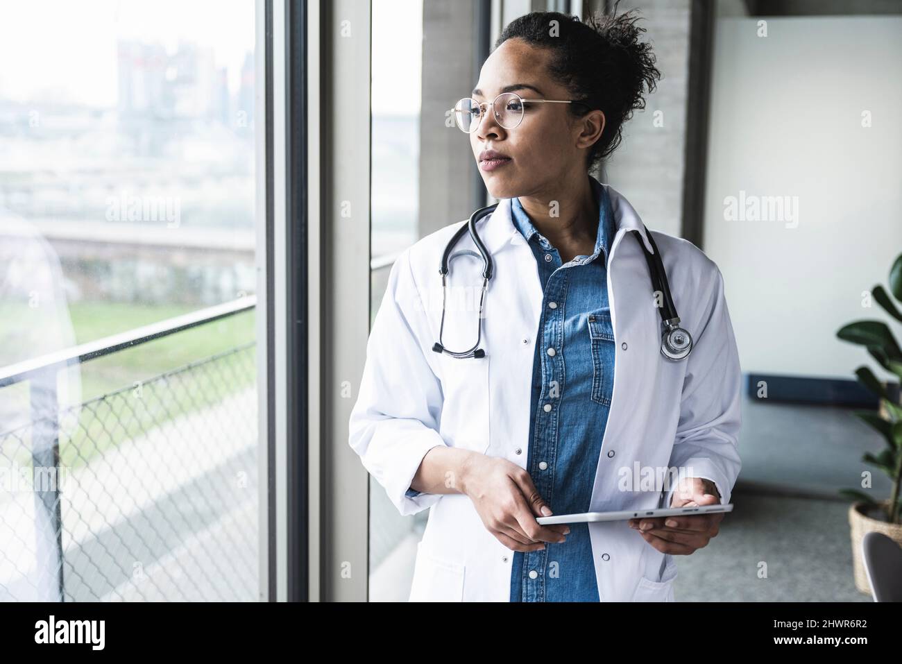 Contemplative doctor looking through window in clinic Stock Photo - Alamy
