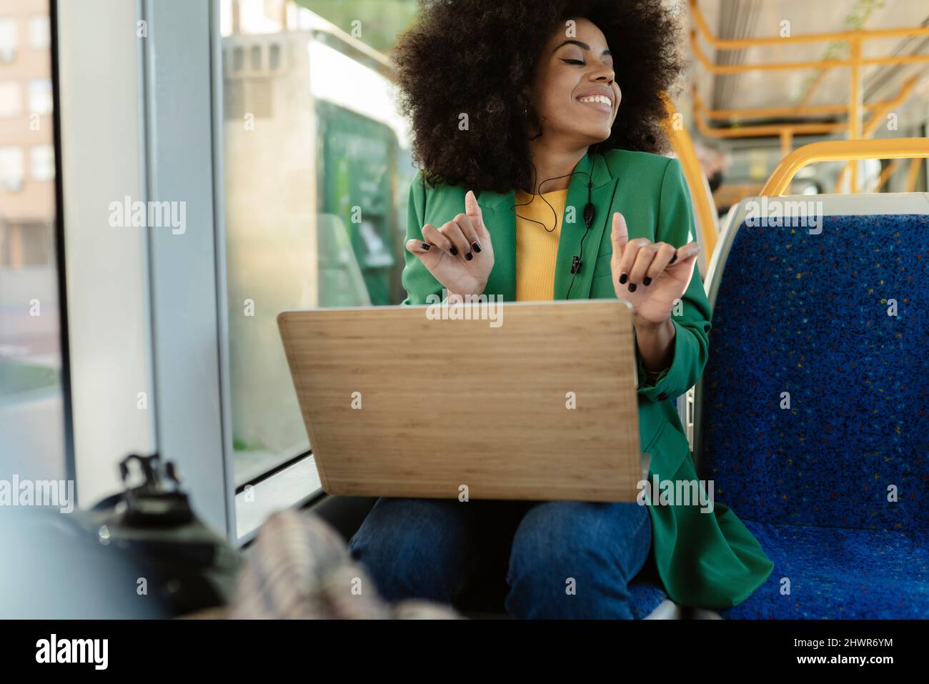 Happy commuter with laptop sitting in tram Stock Photo - Alamy