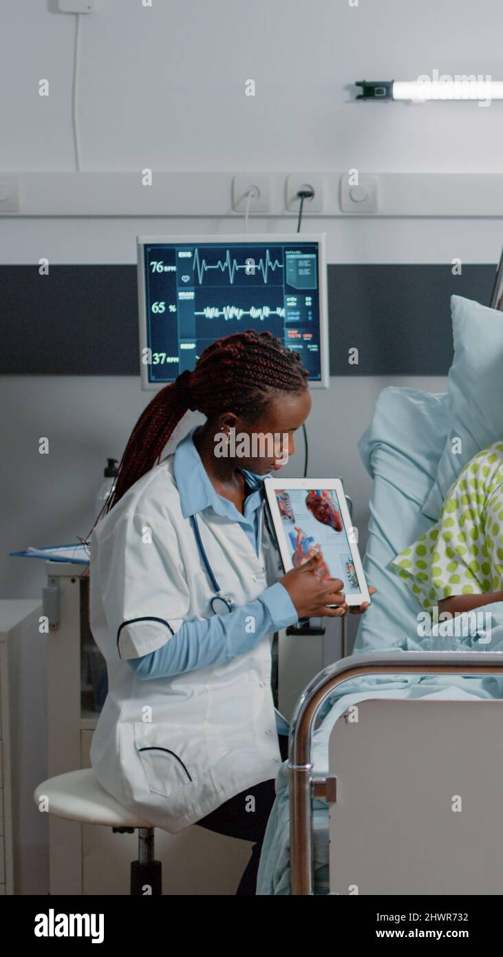 Medic holding tablet with cardiology figure to show diagnosis to woman ...