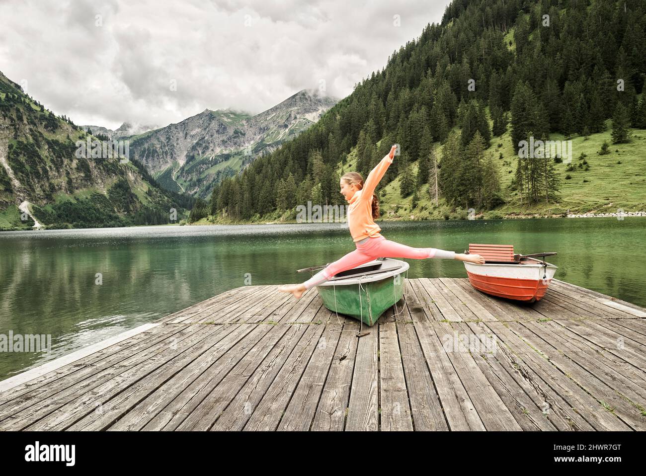 Cheerful girl jumping and doing splits in air over jetty Stock Photo ...