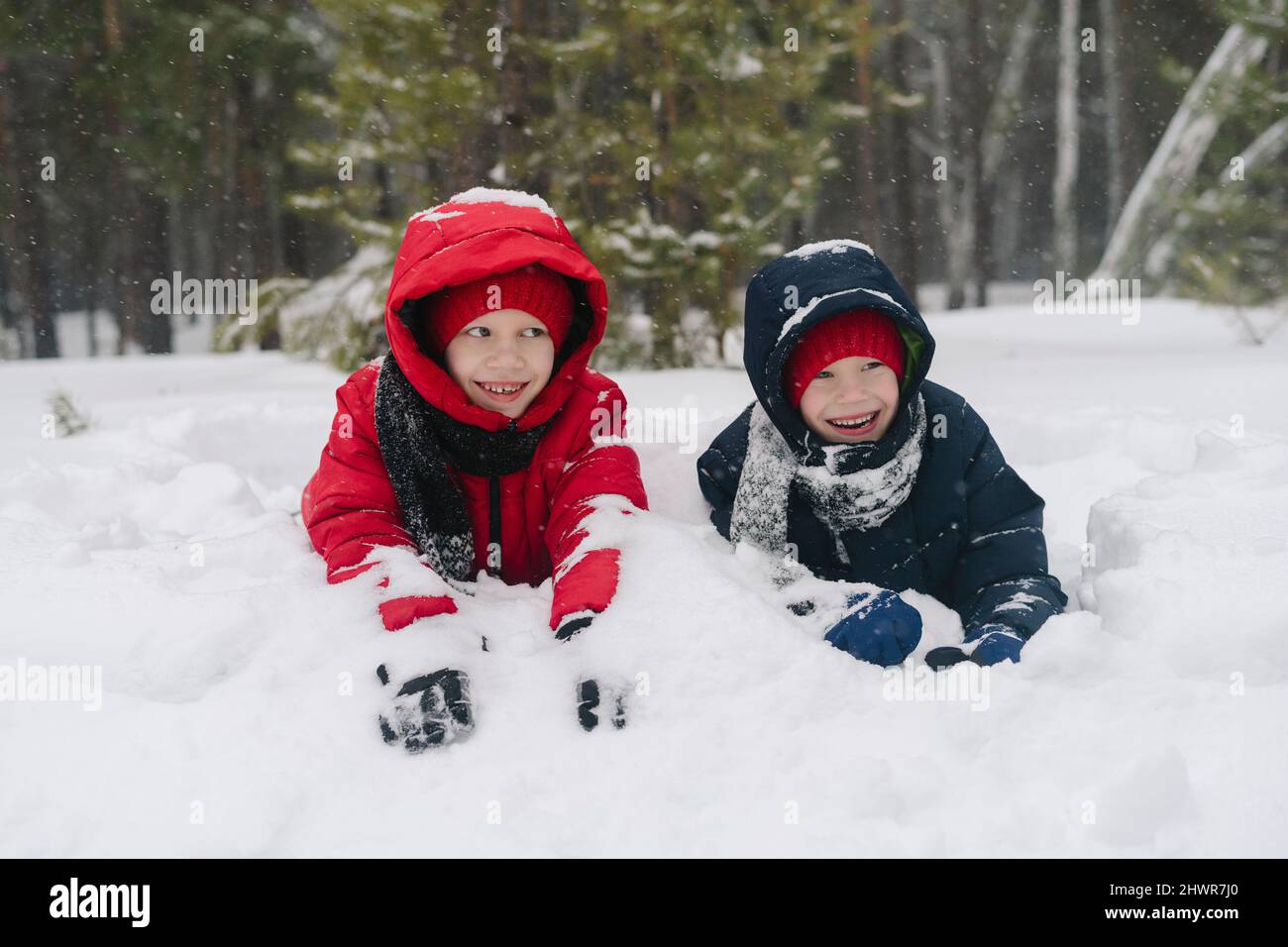 Playful twin brothers lying on snow in winter Stock Photo - Alamy