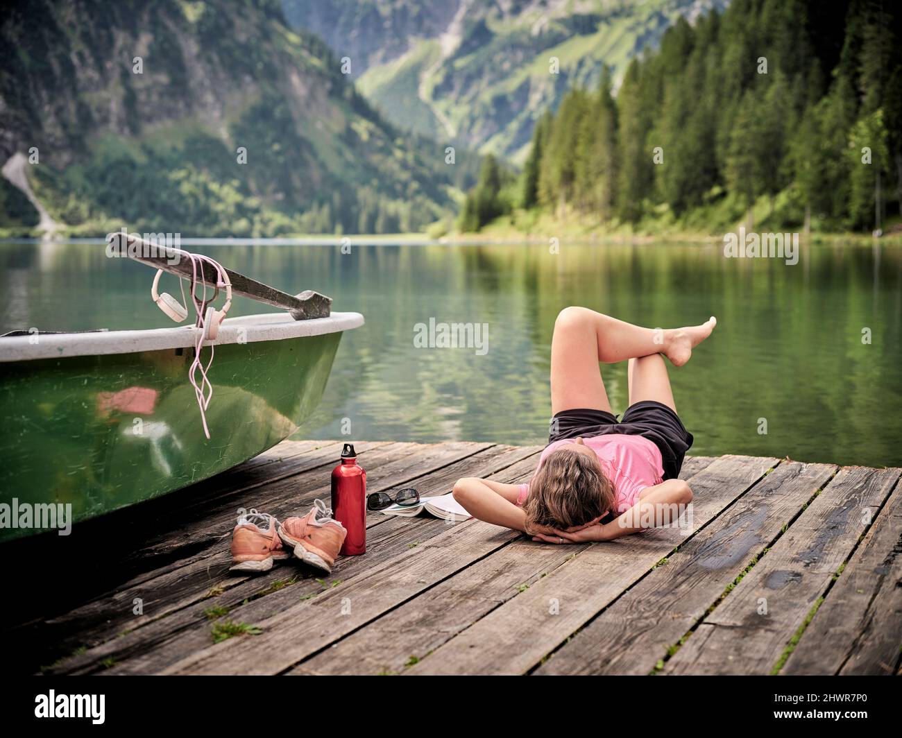 Relaxed woman lying down on jetty by lake Stock Photo - Alamy