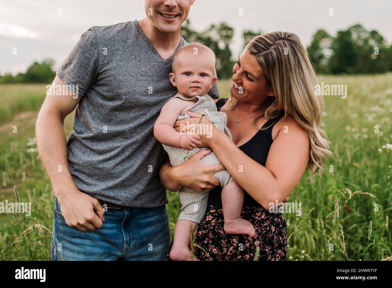 Happy parents with cute baby son standing at garden Stock Photo - Alamy