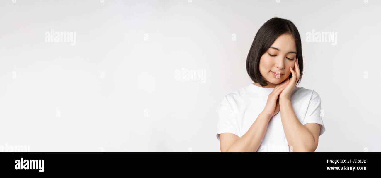 Portrait of tender and feminine young asian woman, looking down, gently ...