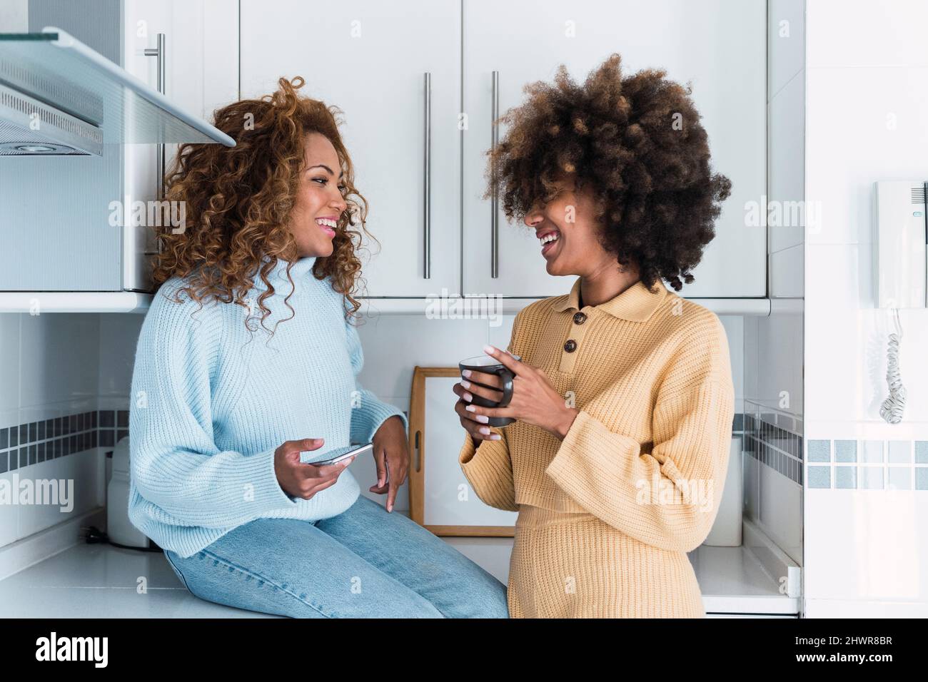 Happy friends talking in kitchen at home Stock Photo - Alamy