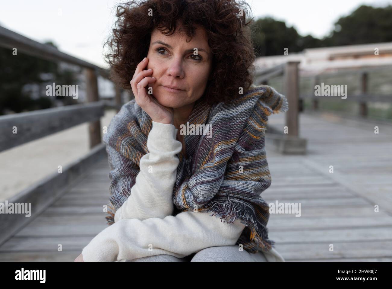 Contemplative woman sitting on footbridge in winter Stock Photo - Alamy