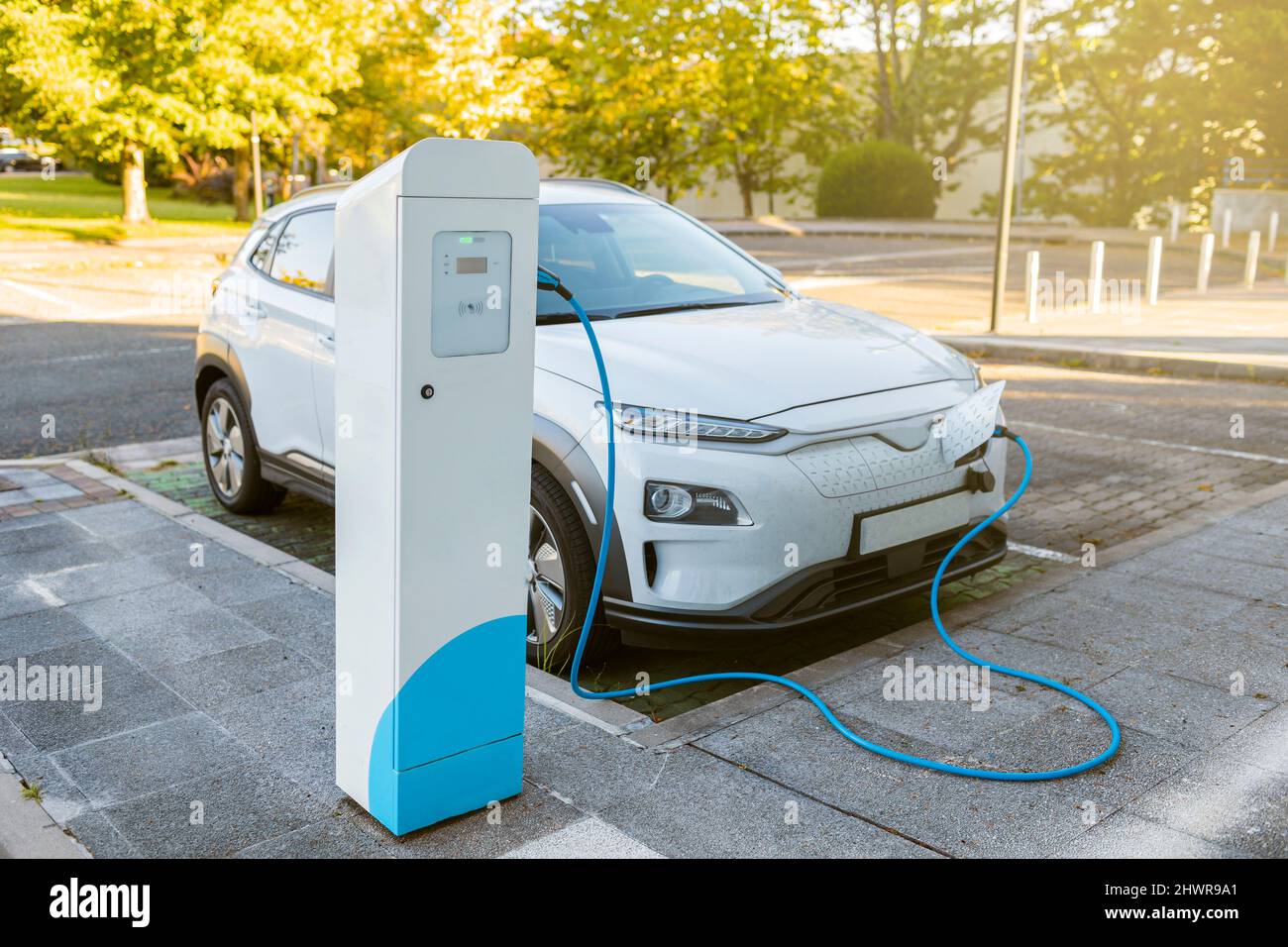 White car charging at electric vehicle charging station Stock Photo - Alamy