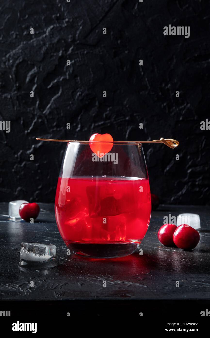 Cocktail with a cherry. Alcohol drink on a black background, with ice ...