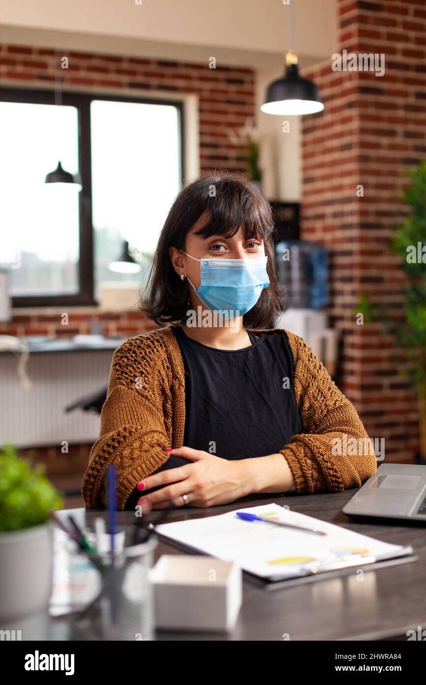 Portrait of bookkeeper woman with medical protection face mask looking ...