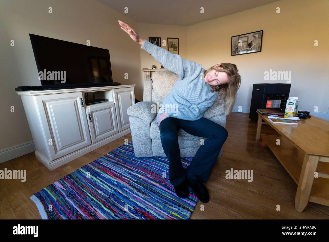 Tall blond woman doing morning stretching exercises in armchair Stock ...