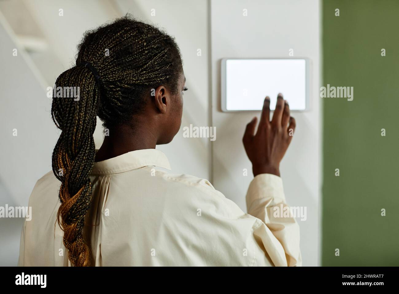 Back view of African American woman using smart home control panel in ...