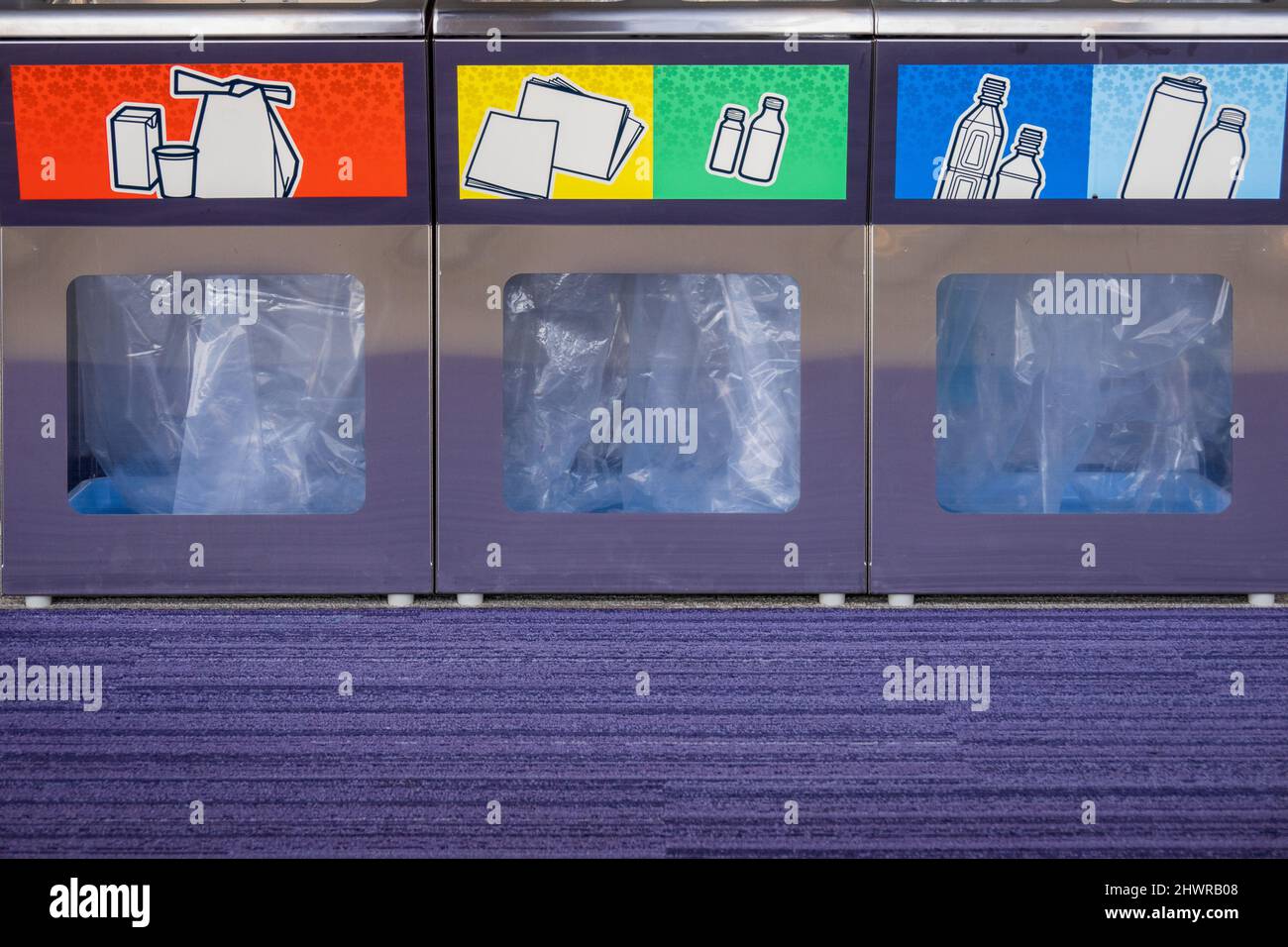 Colorful signs on recycling bins for plastic bottles, paper, and cans ...