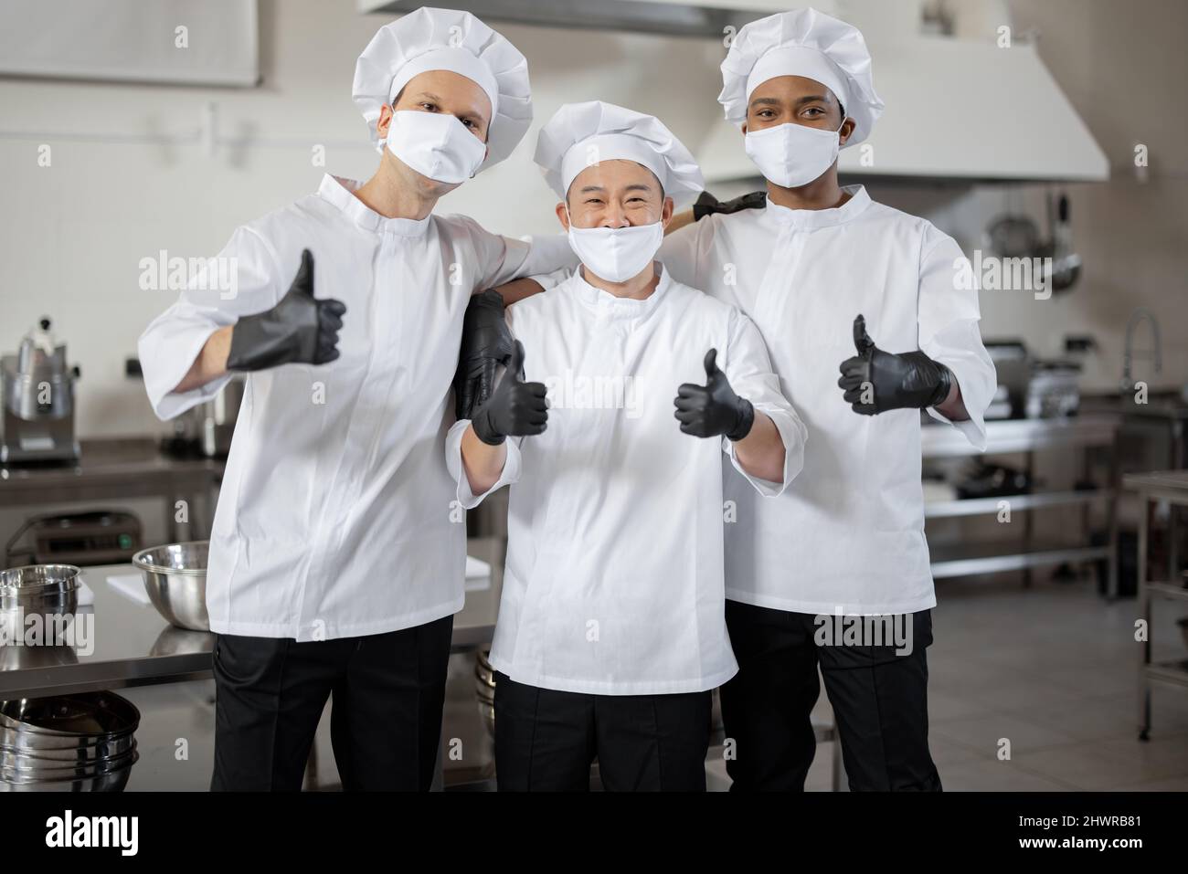 Portrait of multiracial team of three chefs standing together and ...
