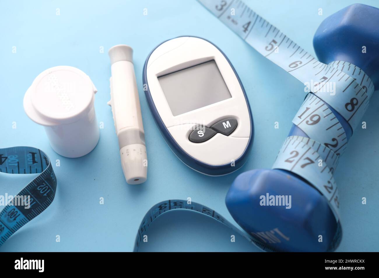 Close up of diabetic measurement tools and dumbbell blue background ...