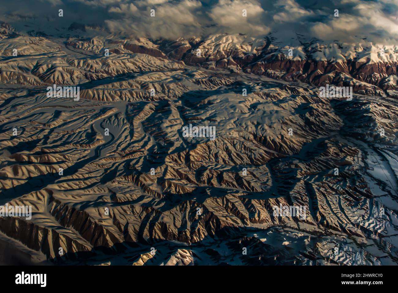 Aerial view from the plane of hills snow and mountains landscape with ...